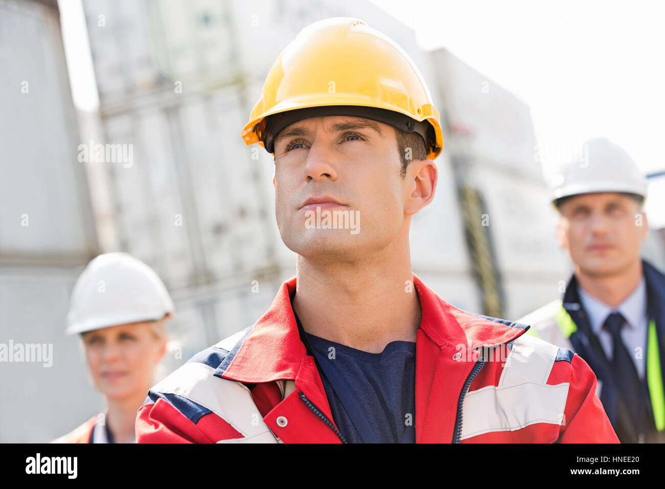 Confident male worker with colleague in background at shipping yard ...