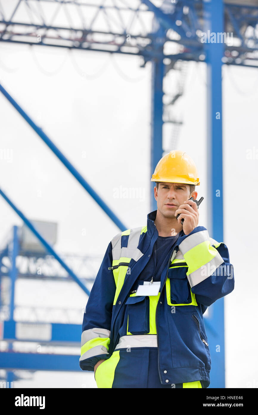 Mid adult male worker using walkie-talkie in shipping yard Stock Photo ...