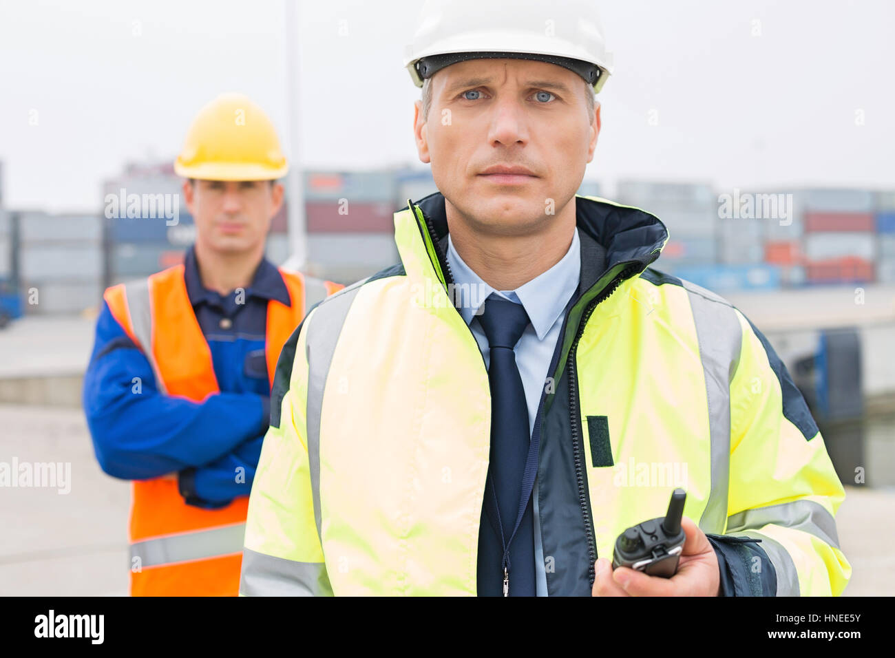 Portrait of confident worker standing with coworker in background at ...