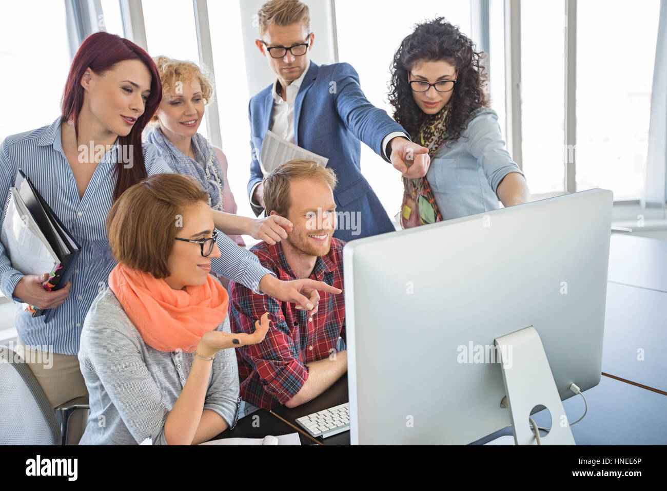 Group of smiling businesspeople using computer together in office Stock ...