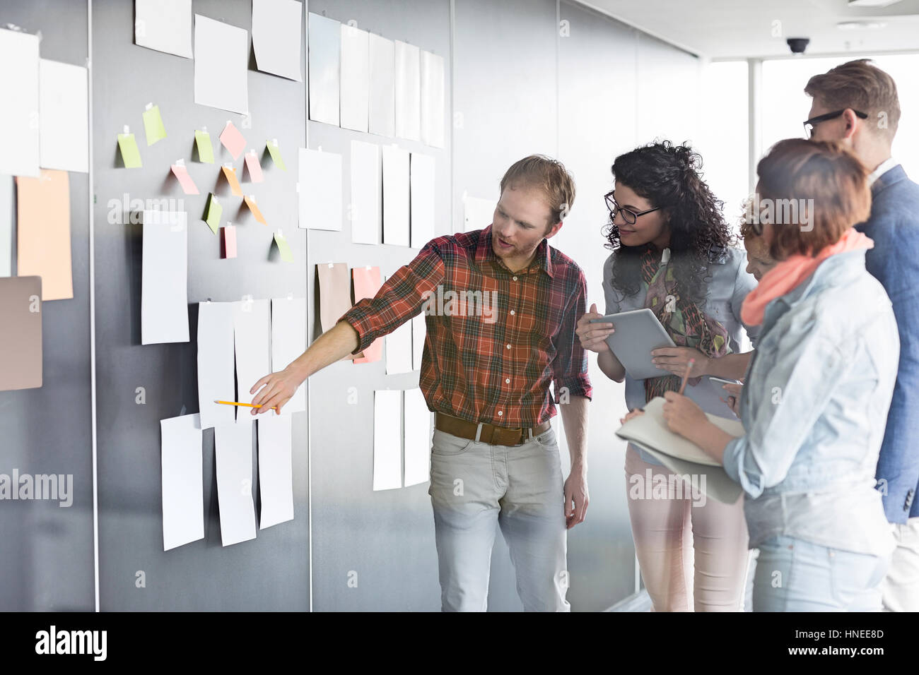 Young businessman explaining document to colleagues in creative office ...