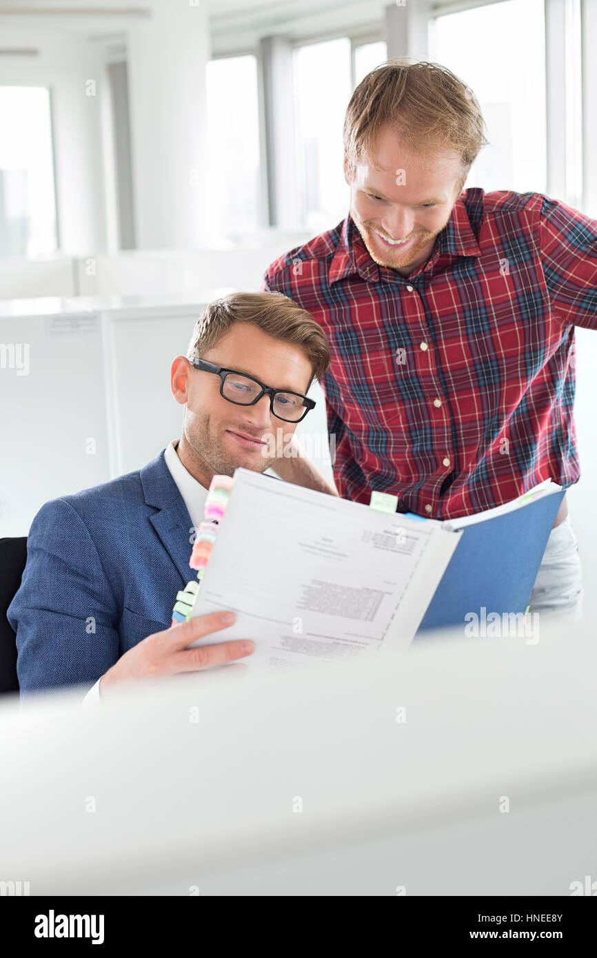Businessmen reading file in creative office Stock Photo - Alamy