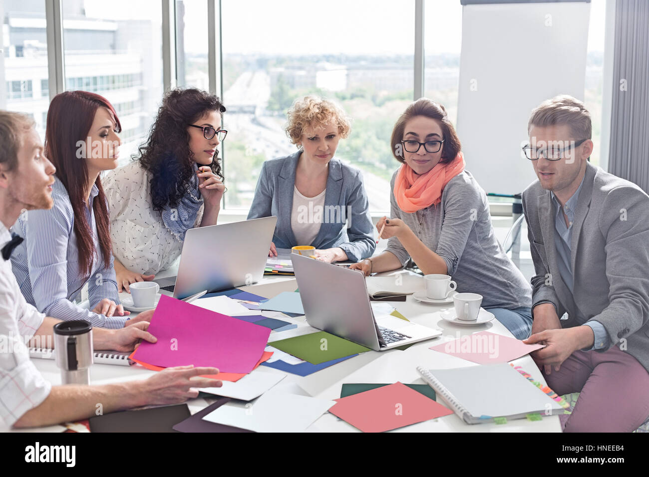 Creative business colleagues analyzing photographs at conference table ...