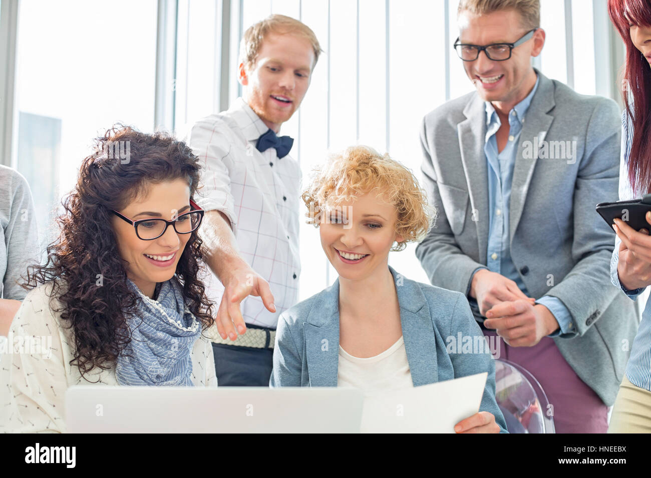 Happy businesspeople working on laptop in creative office Stock Photo ...