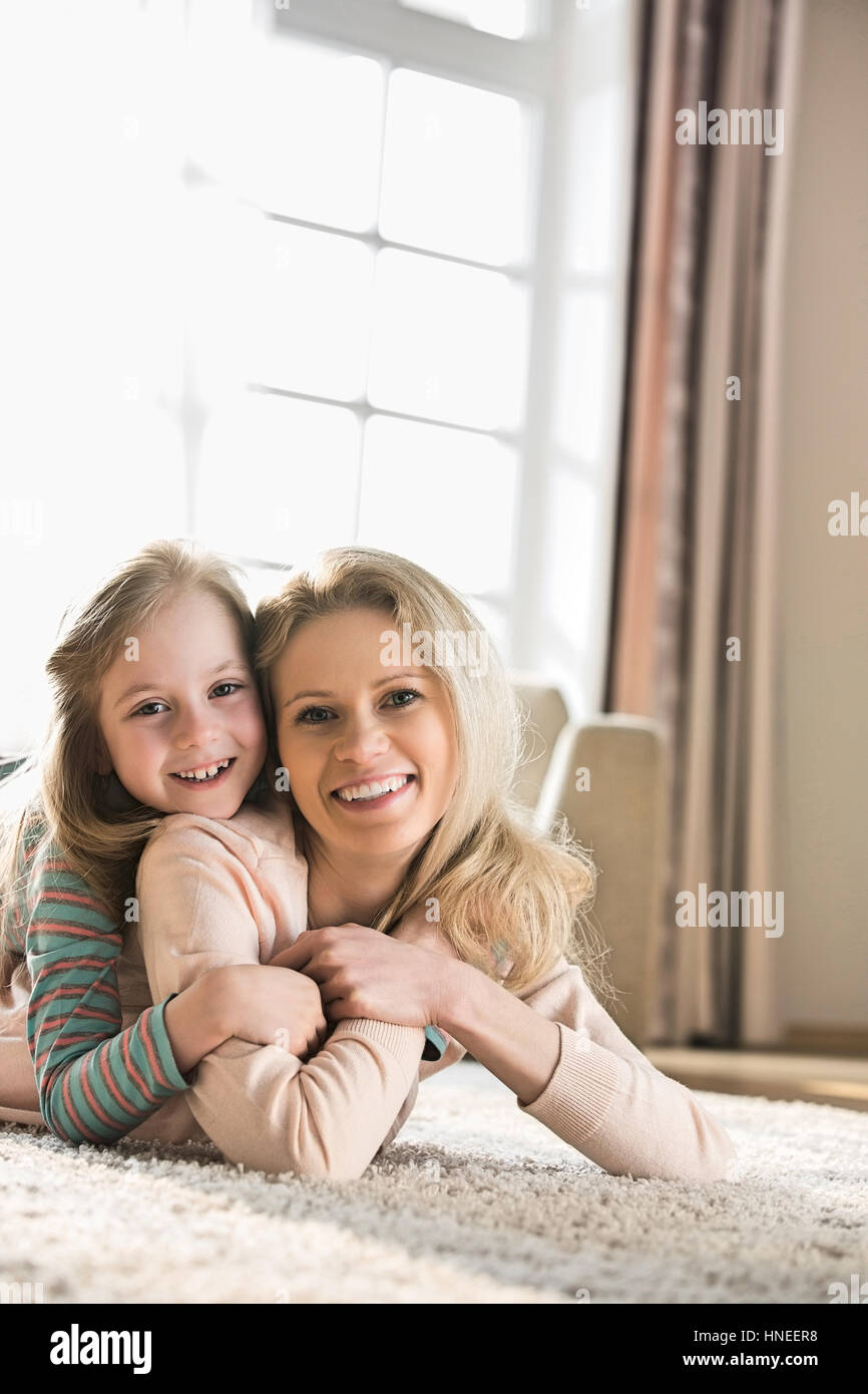 Portrait of happy mother and daughter lying on floor at home Stock ...