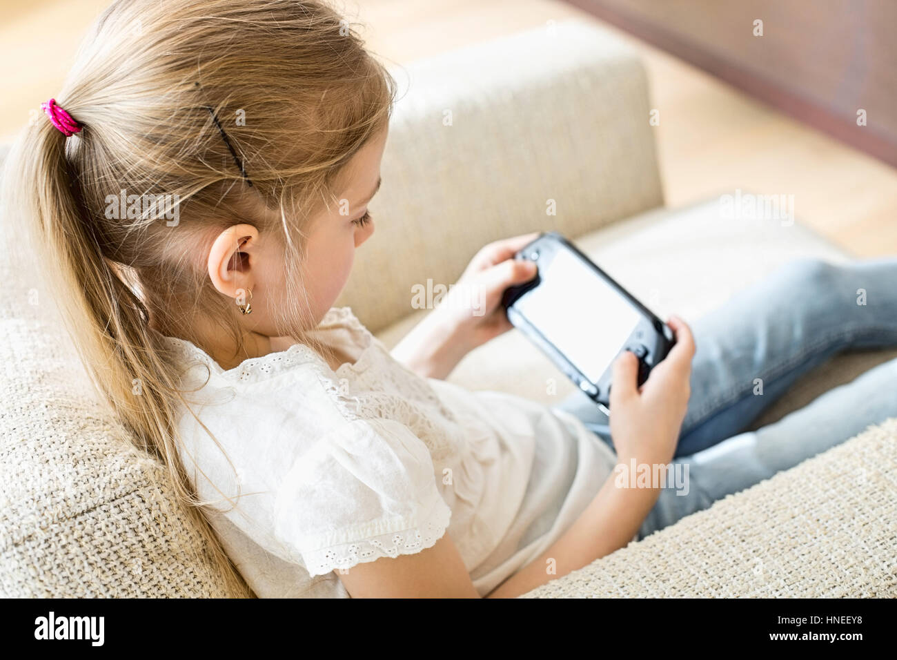 Rear view of girl playing hand-held video game at home Stock Photo - Alamy