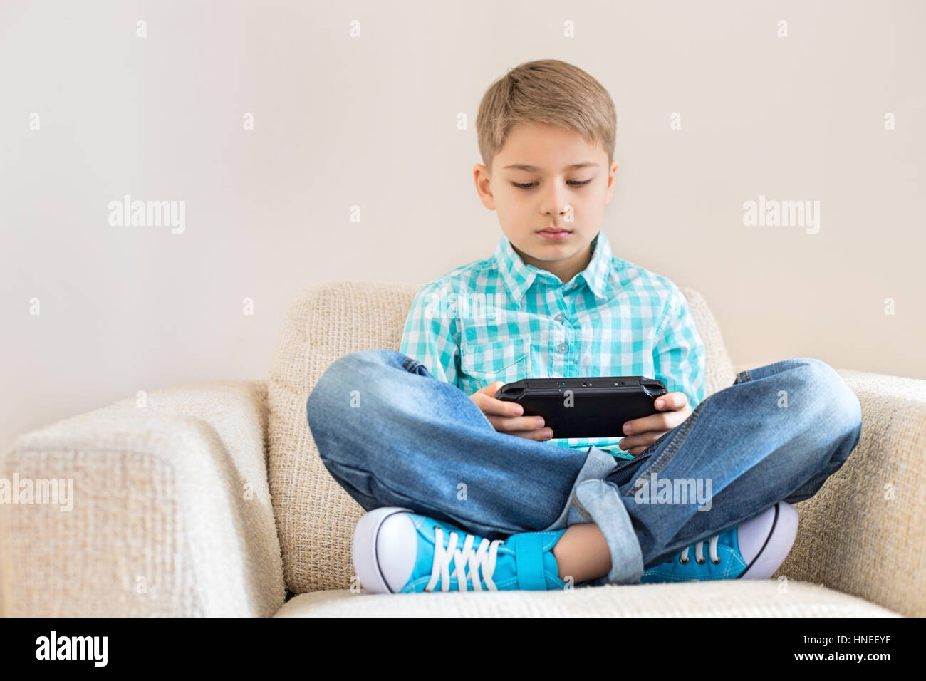 Boy playing hand-held video game on sofa Stock Photo - Alamy
