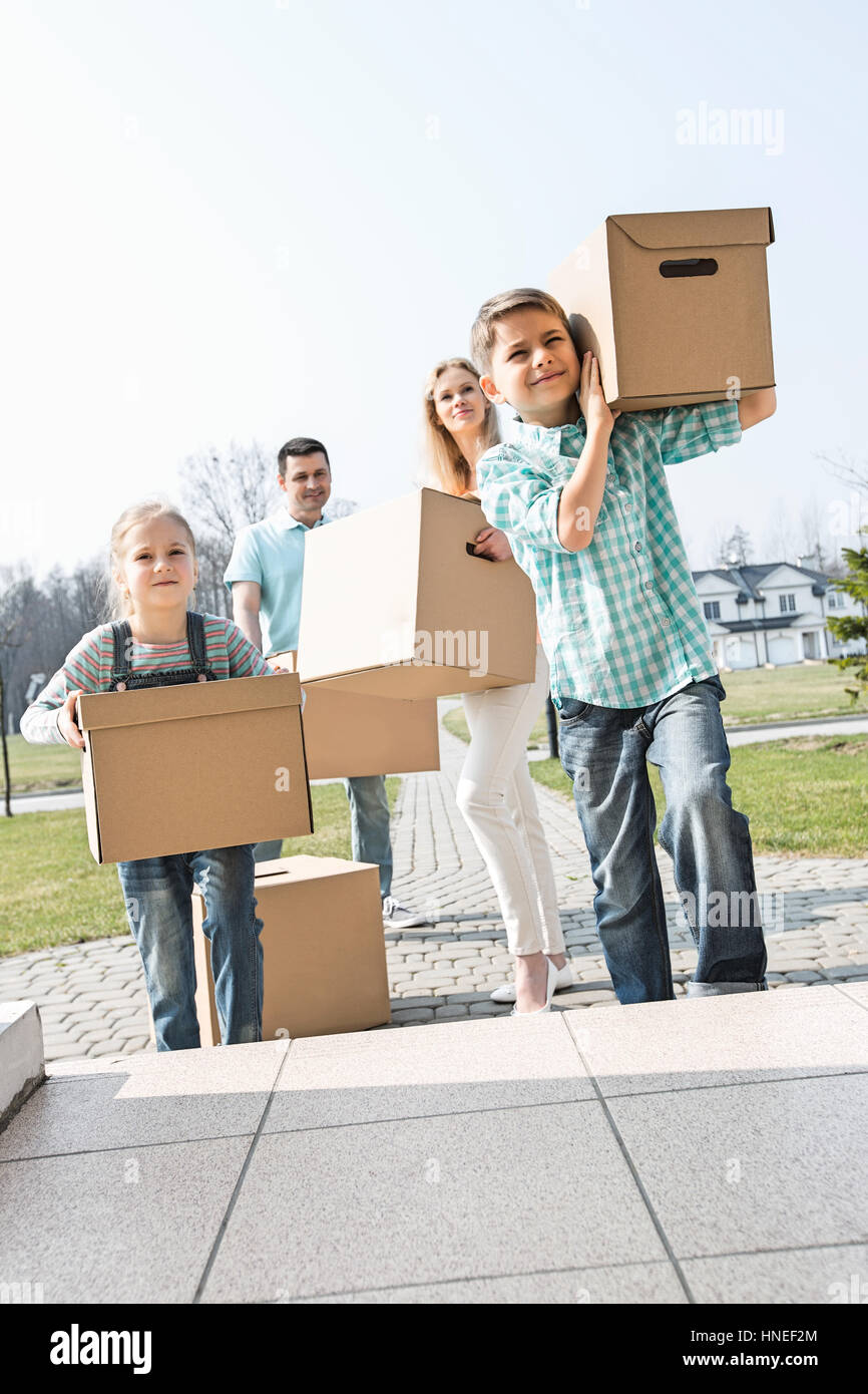 Family carrying cardboard boxes while entering new house Stock Photo ...