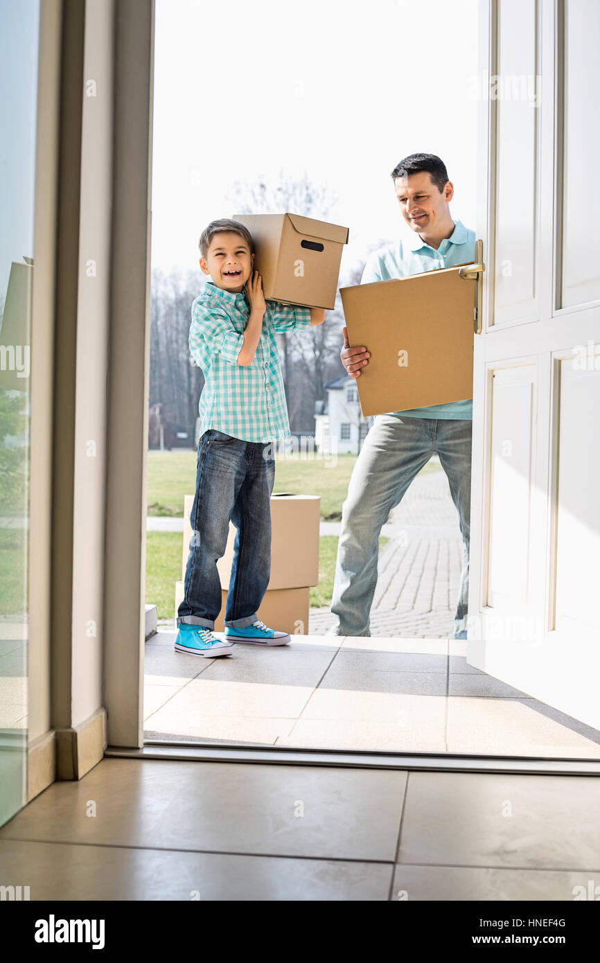 Happy father and son with cardboard boxes entering into new house Stock ...