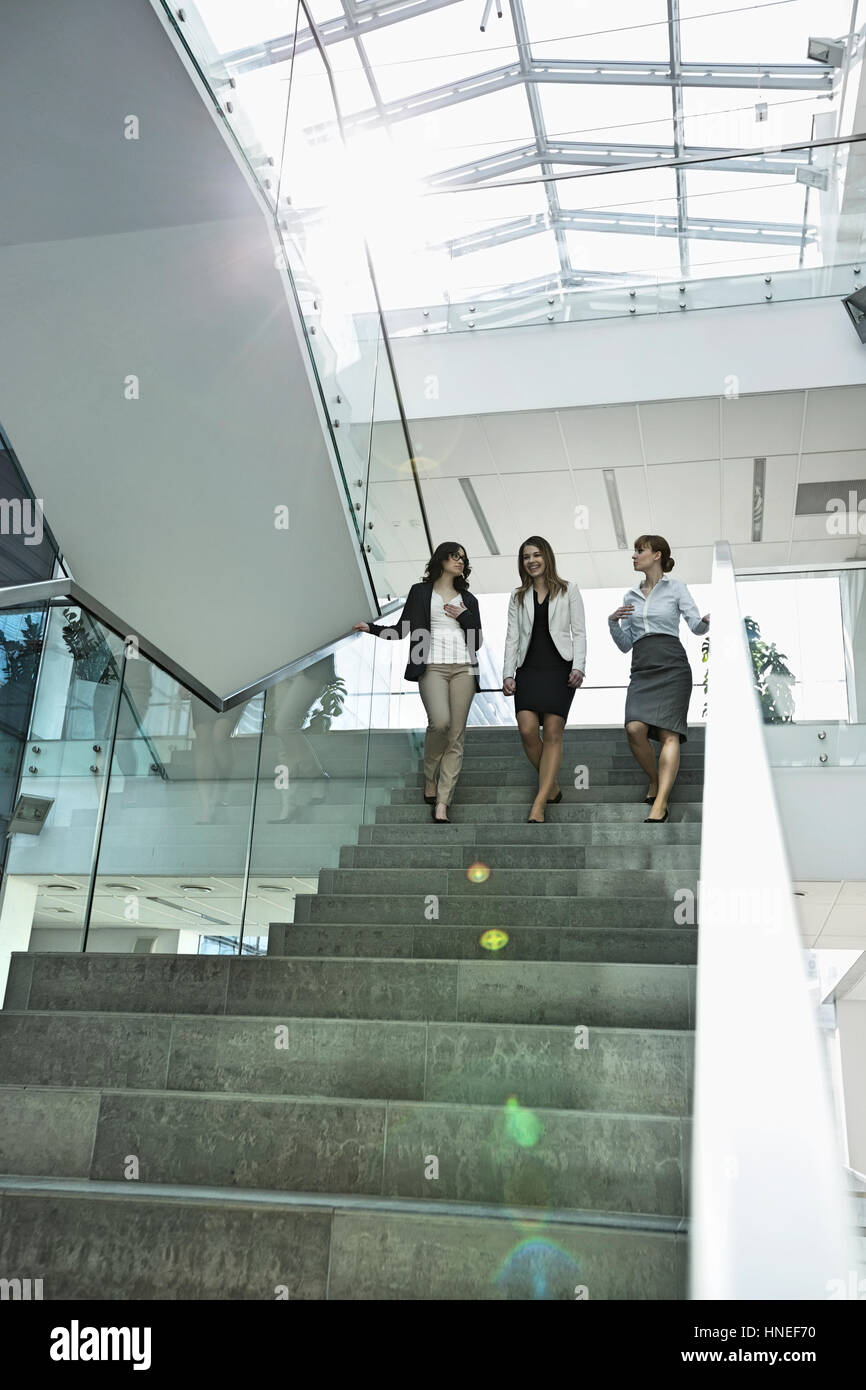 Happy businesswomen conversing while moving down steps in office Stock ...