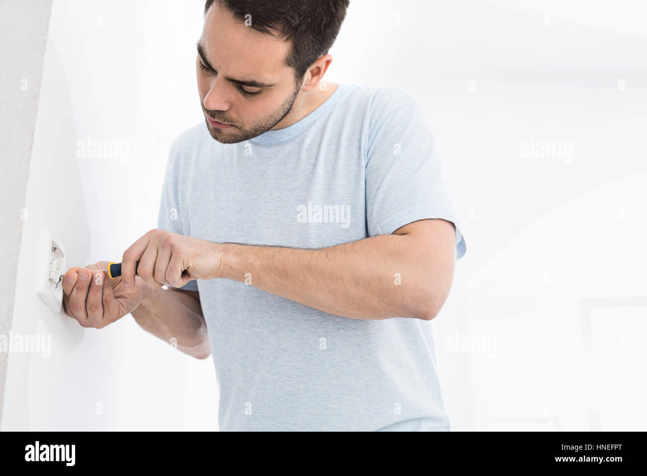 Man working on electrical outlet Stock Photo - Alamy