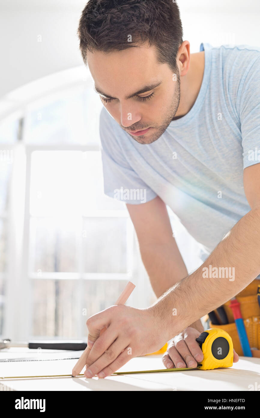 Mid-adult man marking table with measure tape Stock Photo - Alamy