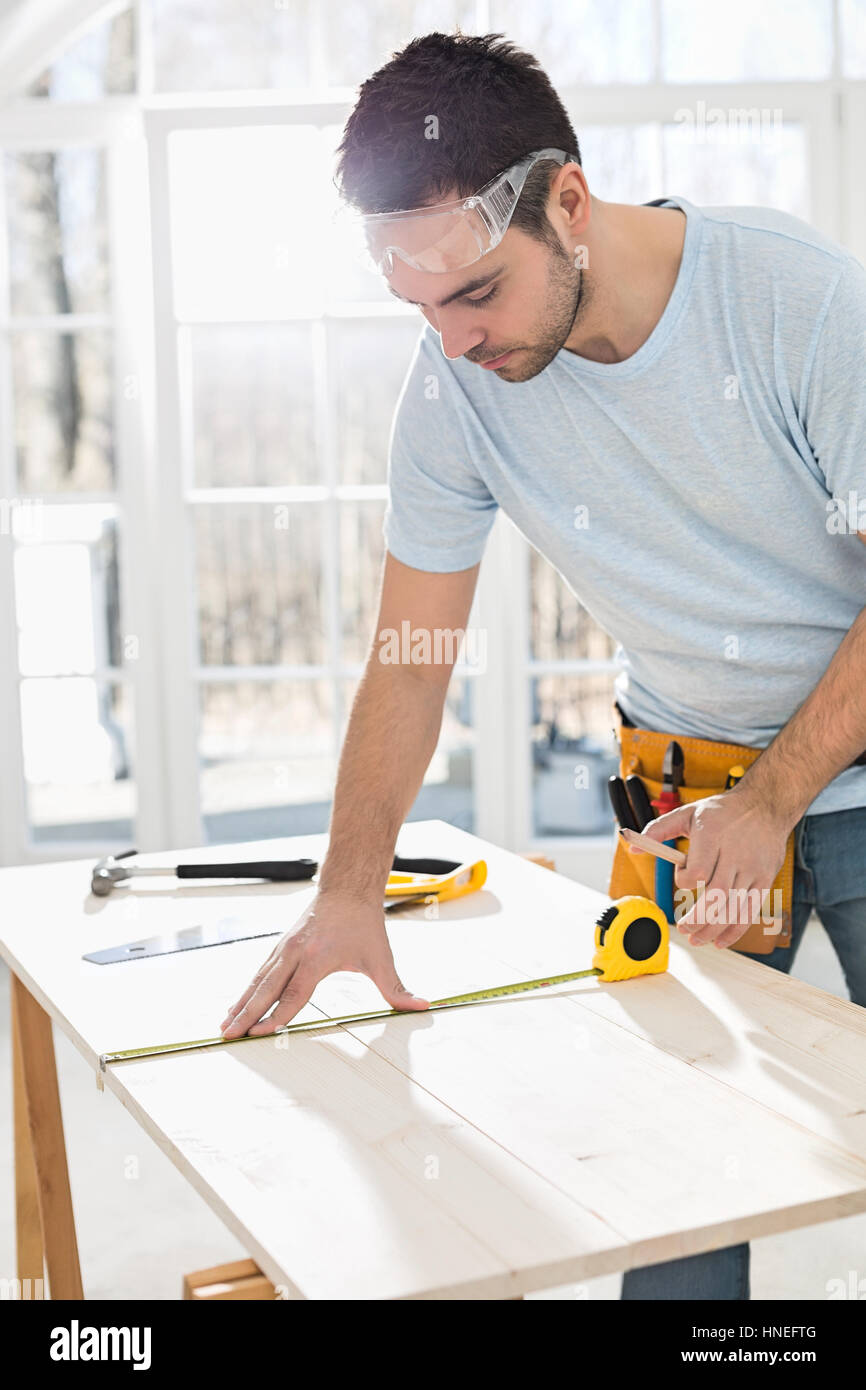 Mid-adult man marking table with measure tape Stock Photo - Alamy