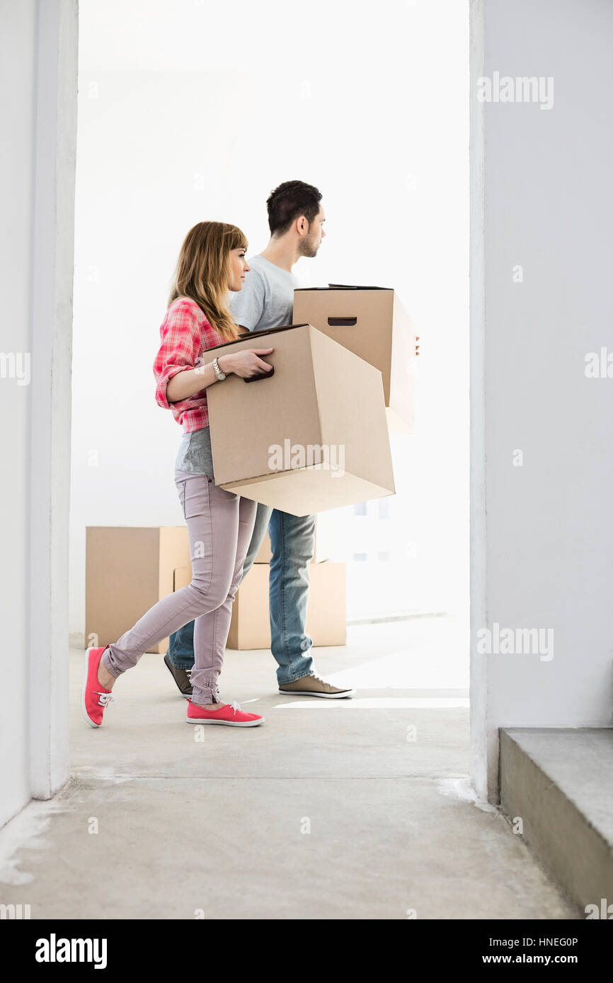 Full-length side view of couple walking with cardboard boxes Stock ...