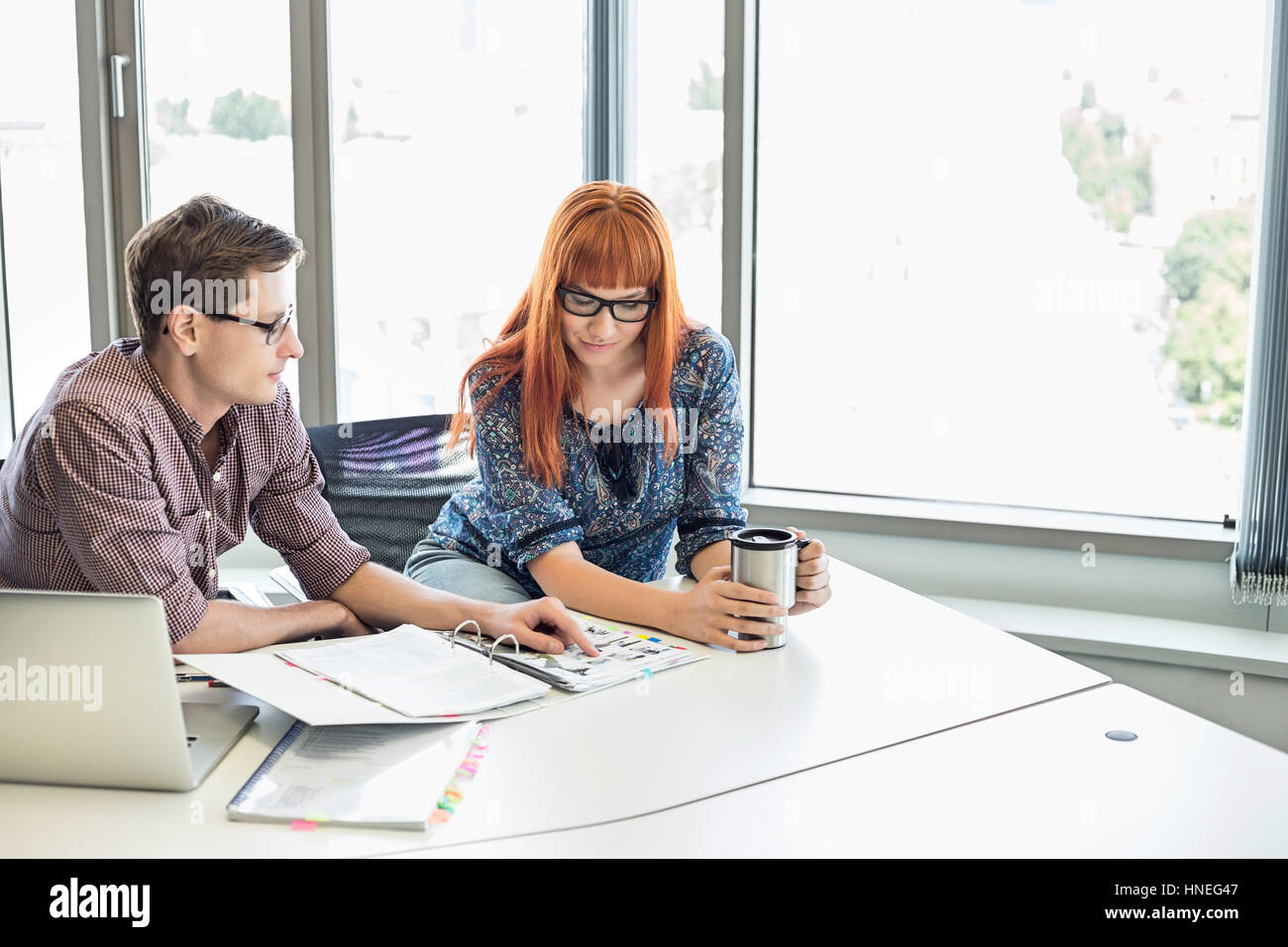 Creative business colleagues reading file together at desk in office ...