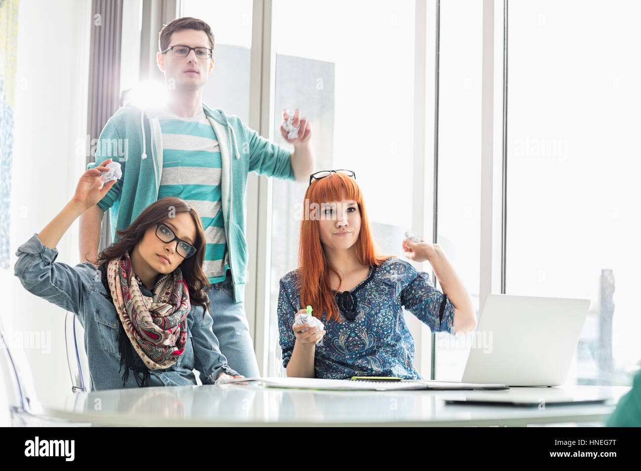 Angry businesspeople throwing paper balls in creative office Stock ...