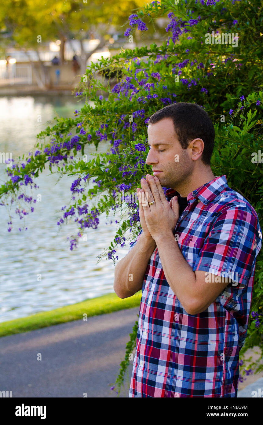 Man praying by a lake alone by a pathway Stock Photo - Alamy