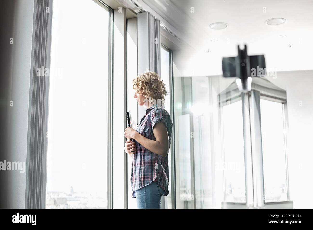 Side view of creative businesswoman holding files while looking through ...
