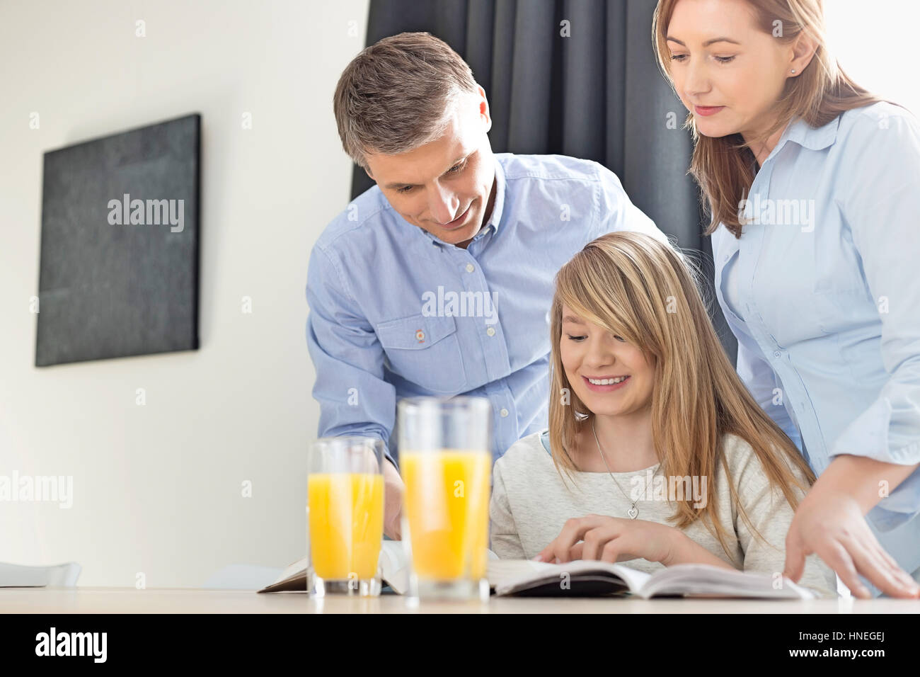 Happy parents assisting daughter in homework at home Stock Photo - Alamy