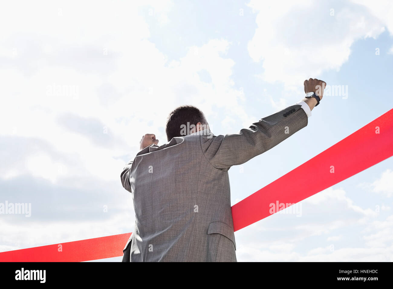 Rear view of businessman crossing finish line against sky Stock Photo ...