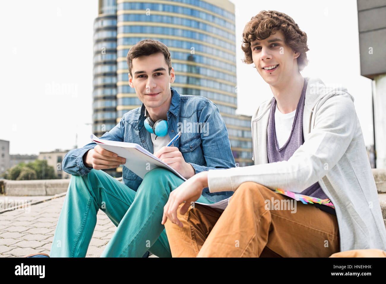 Portrait of young male college students studying on steps against ...