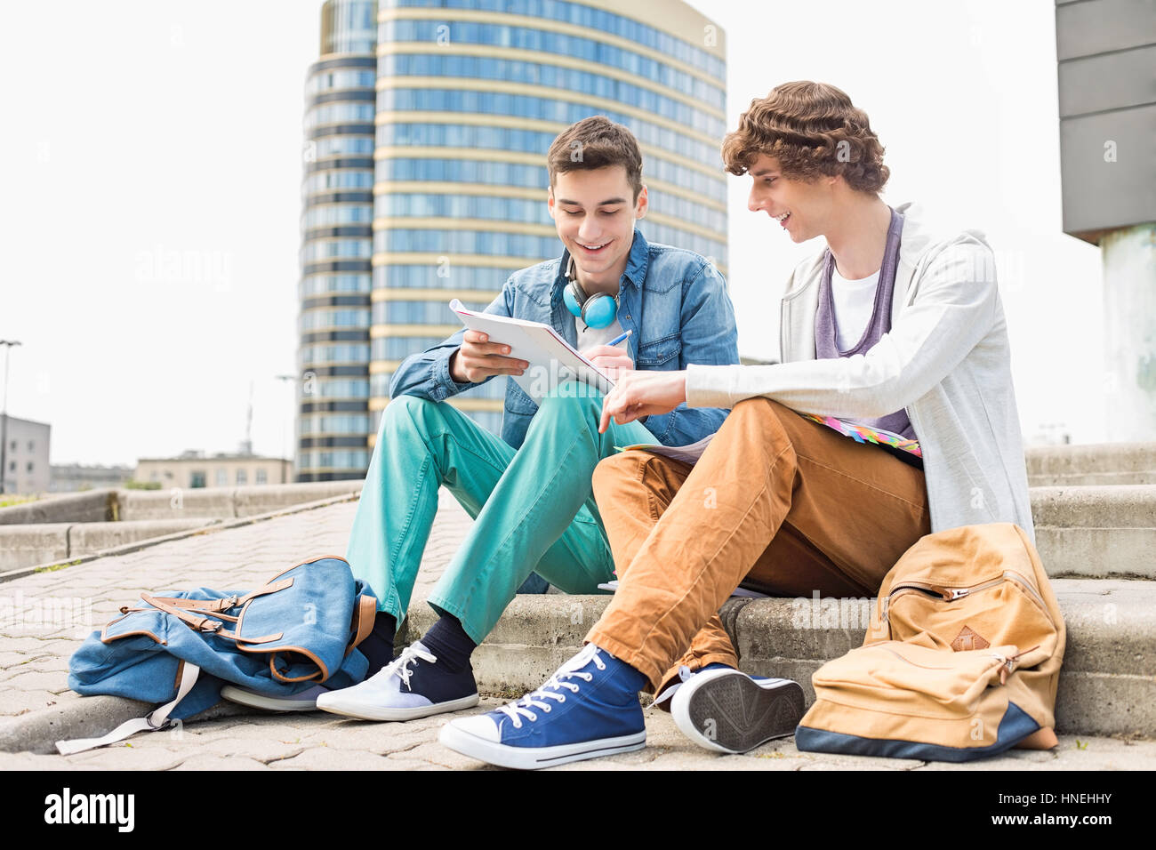 Full length of young male college students studying on steps against ...