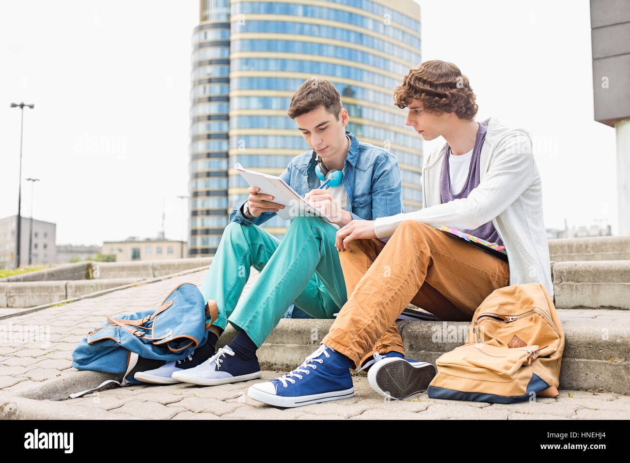 Full length of young male college students studying on steps against ...