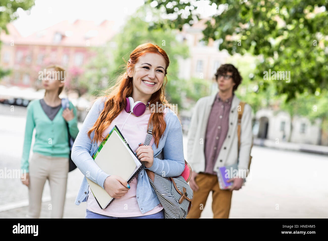 Smiling young female student with friends in background on street Stock ...