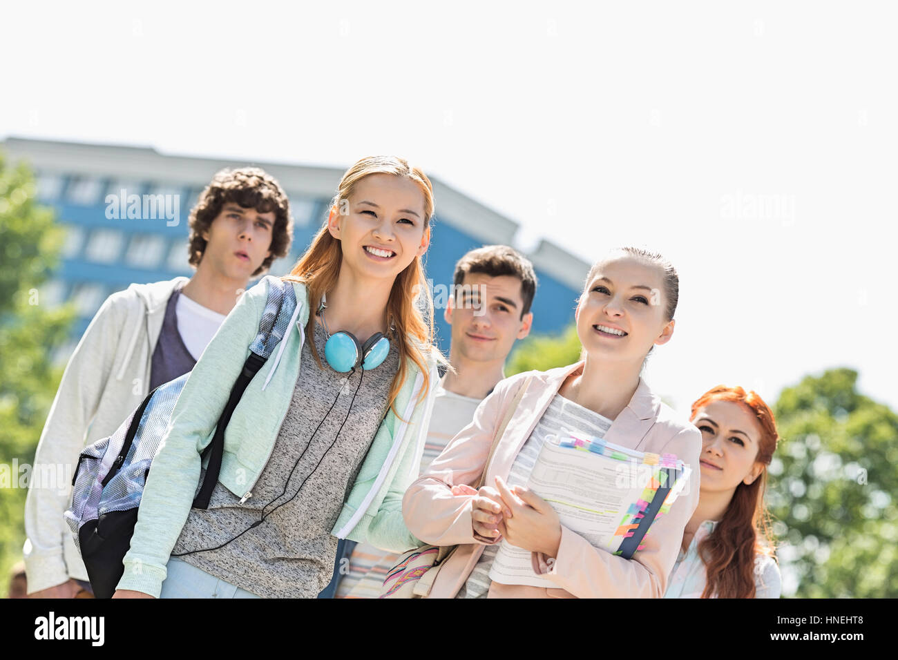 Smiling young students standing together at college campus Stock Photo ...