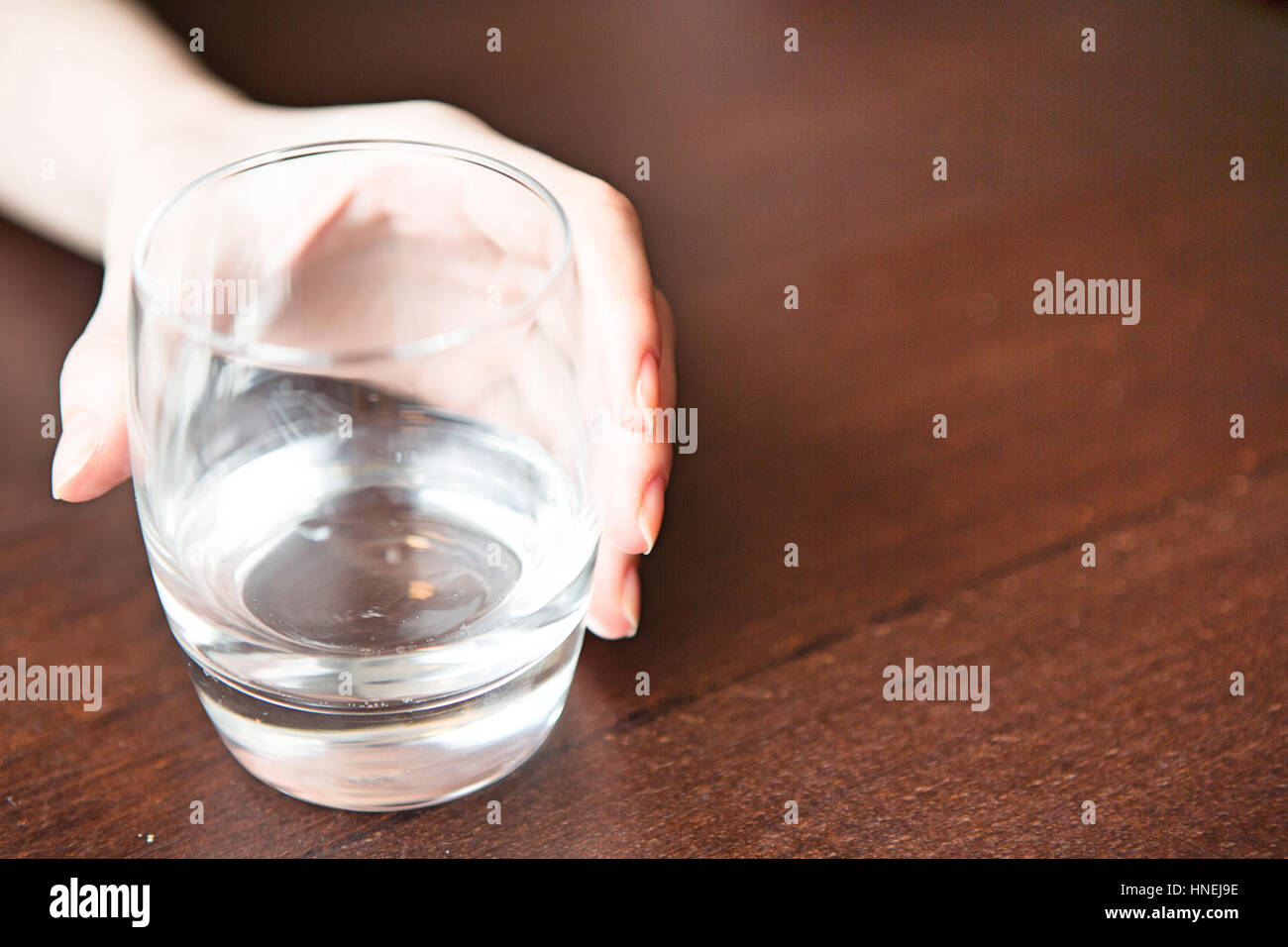 Woman's hand holding glass of water on table Stock Photo - Alamy