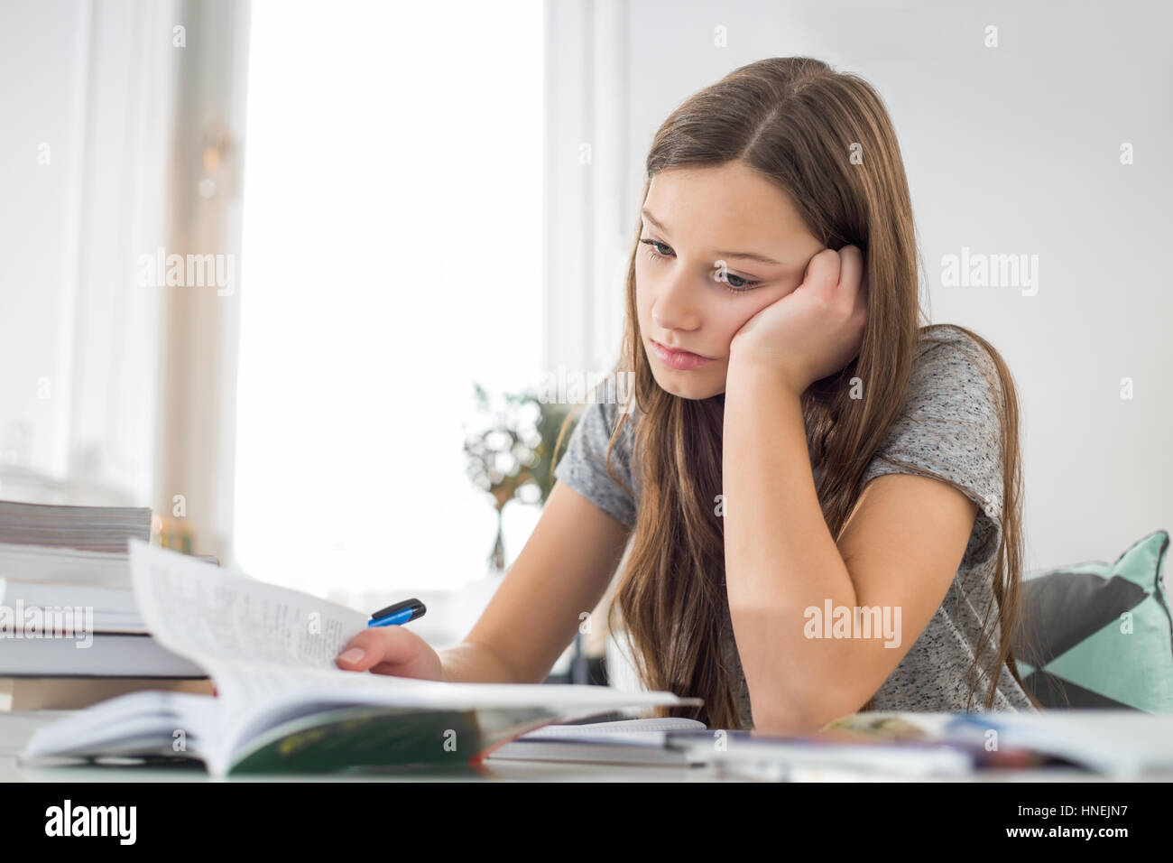 Bored girl studying at table in house Stock Photo - Alamy