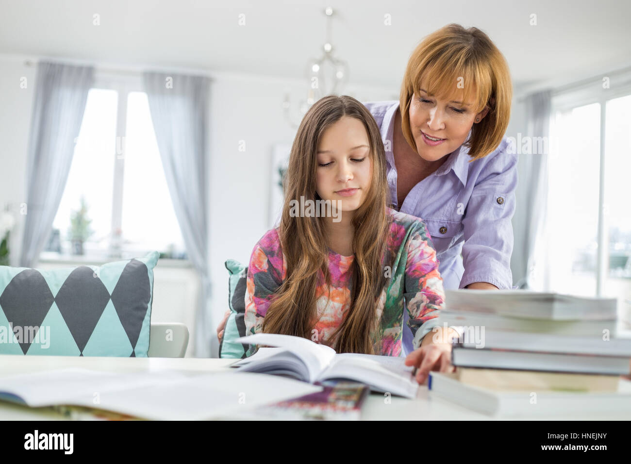 Mother assisting daughter in doing homework at table Stock Photo - Alamy