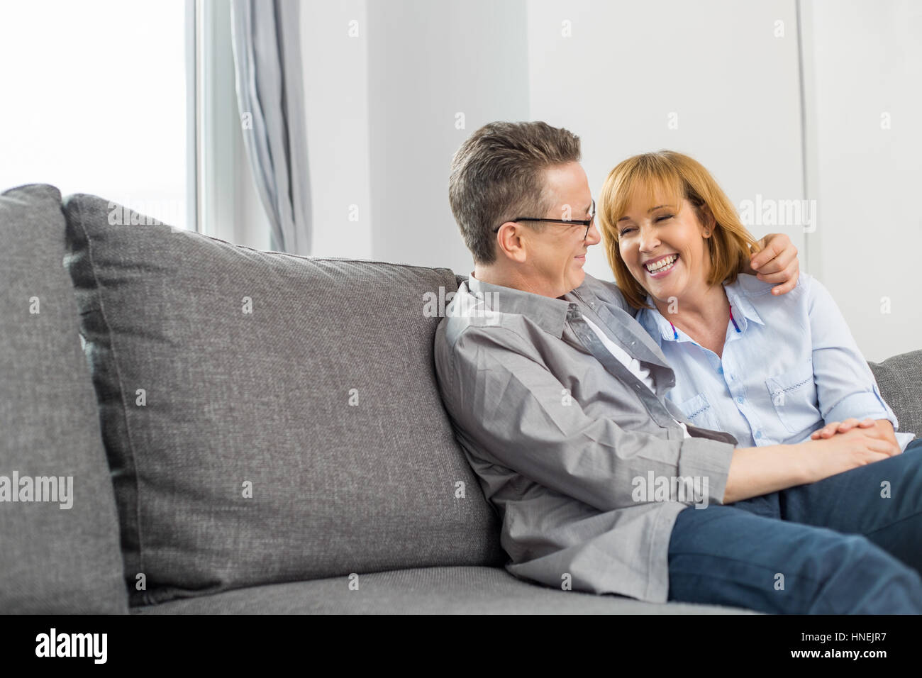 Happy loving couple sitting on sofa at home Stock Photo - Alamy