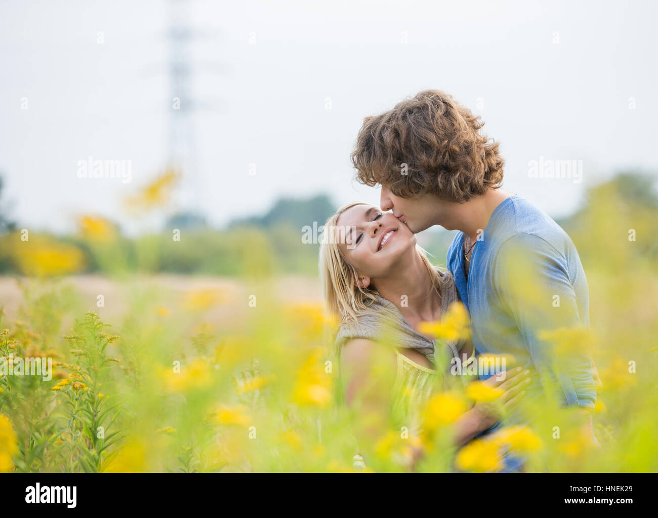 Romantic man kissing woman in field Stock Photo - Alamy