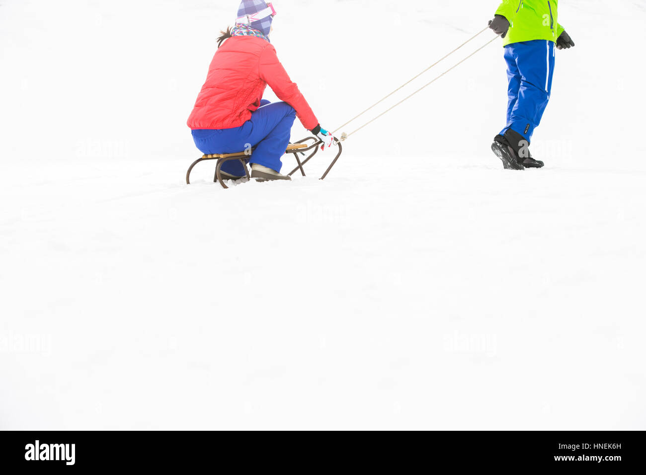 Low section of young man pulling woman on sled Stock Photo - Alamy