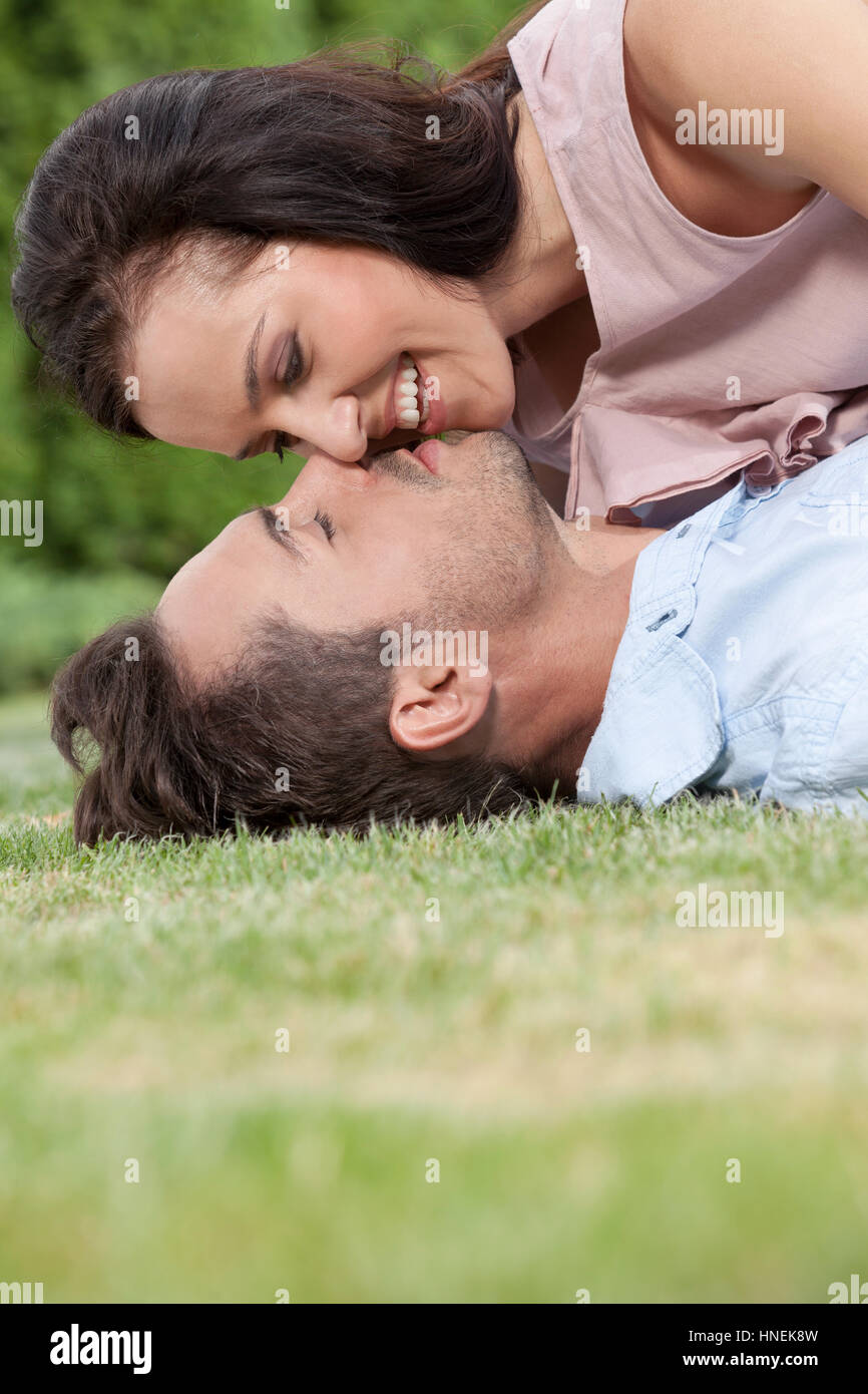 Side view of loving young couple about to kiss in park Stock Photo - Alamy