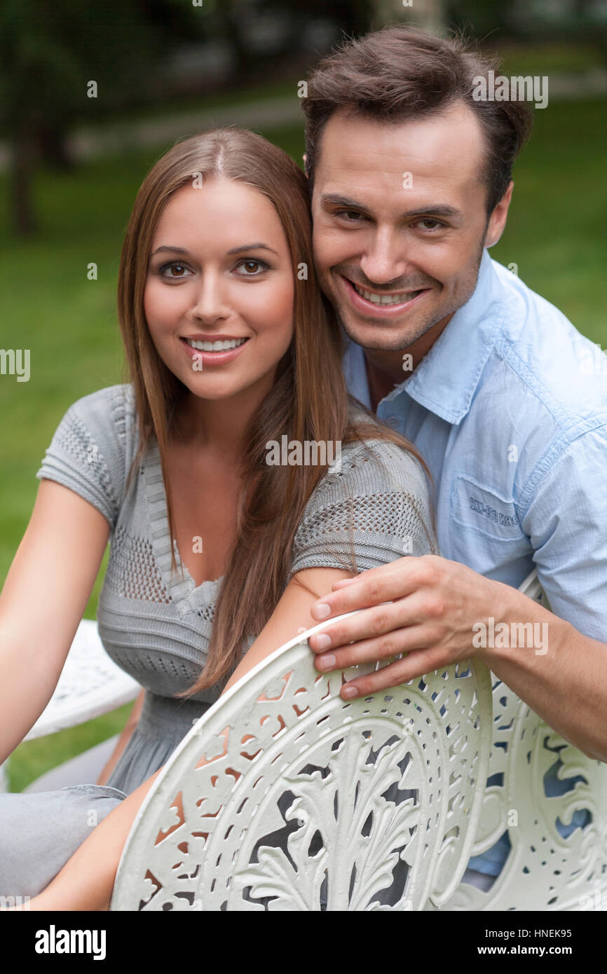 Portrait of loving young couple sitting on chairs in park Stock Photo ...