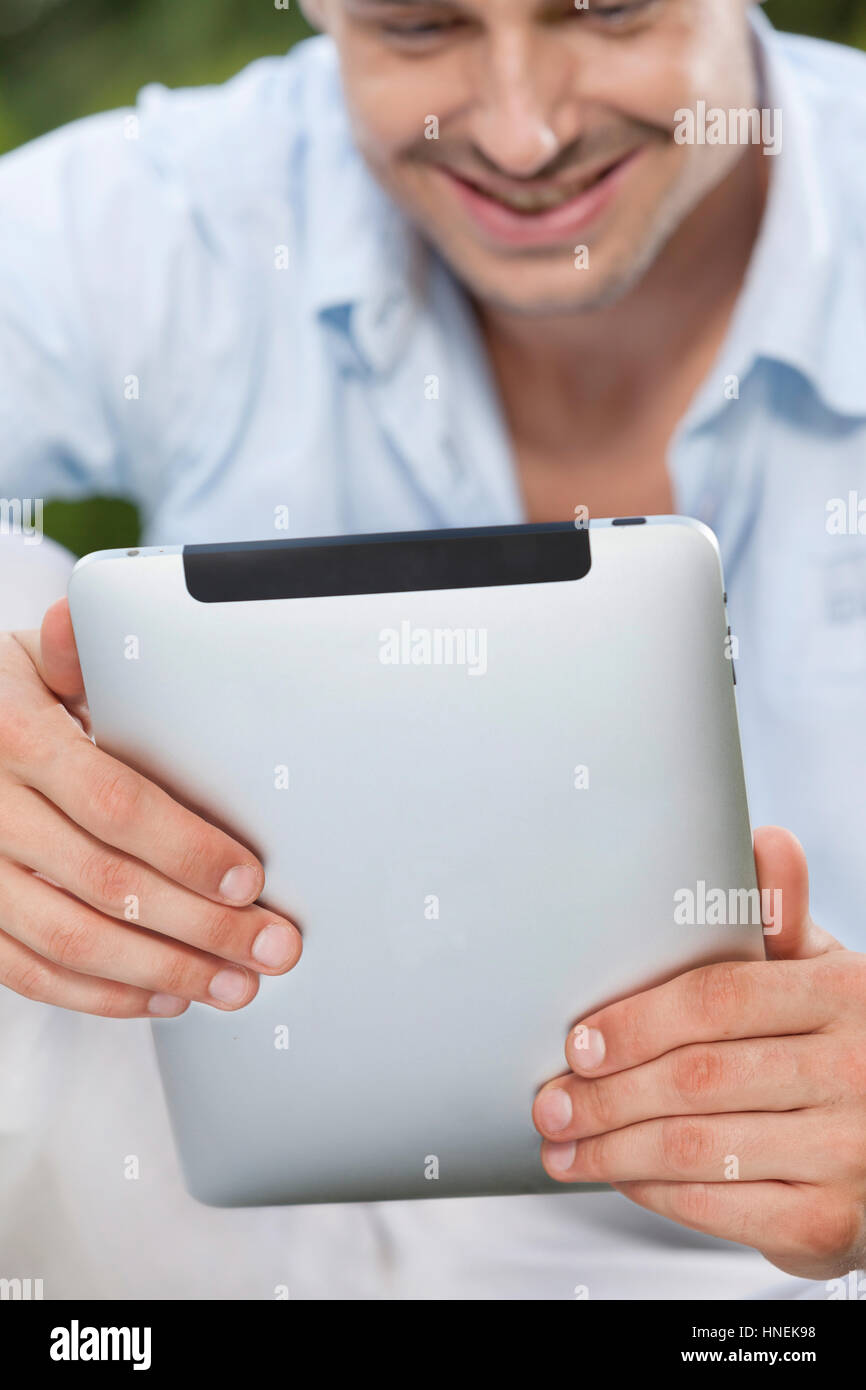 Young man using digital tablet in park Stock Photo - Alamy