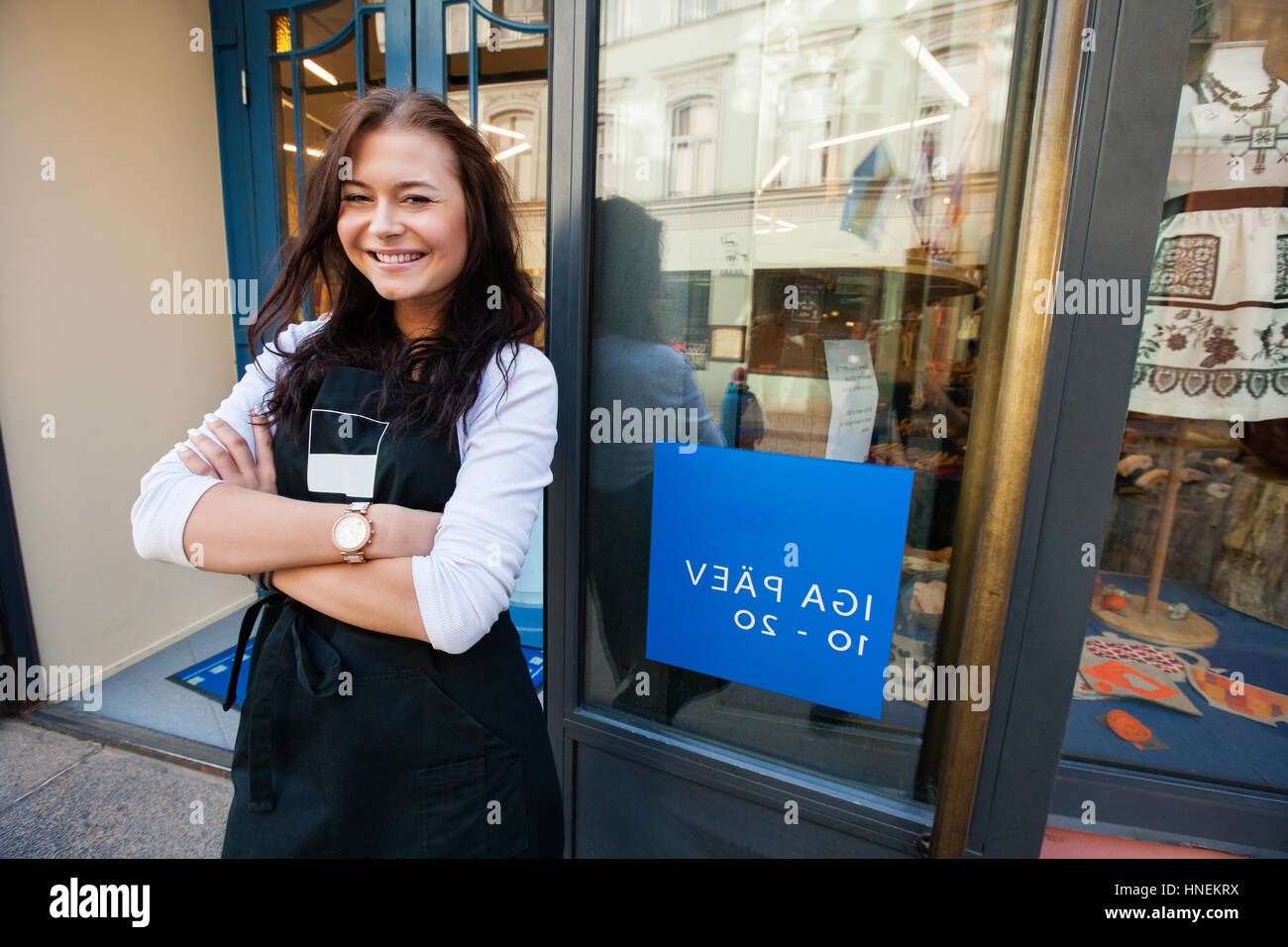 Portrait of smiling saleswoman standing arms crossed outside ...