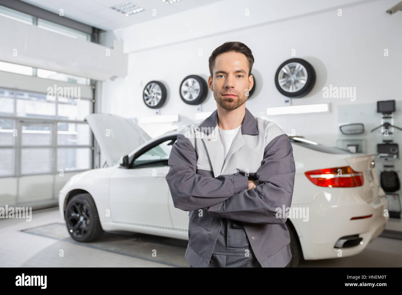 Portrait of confident male automobile mechanic standing in front of car ...