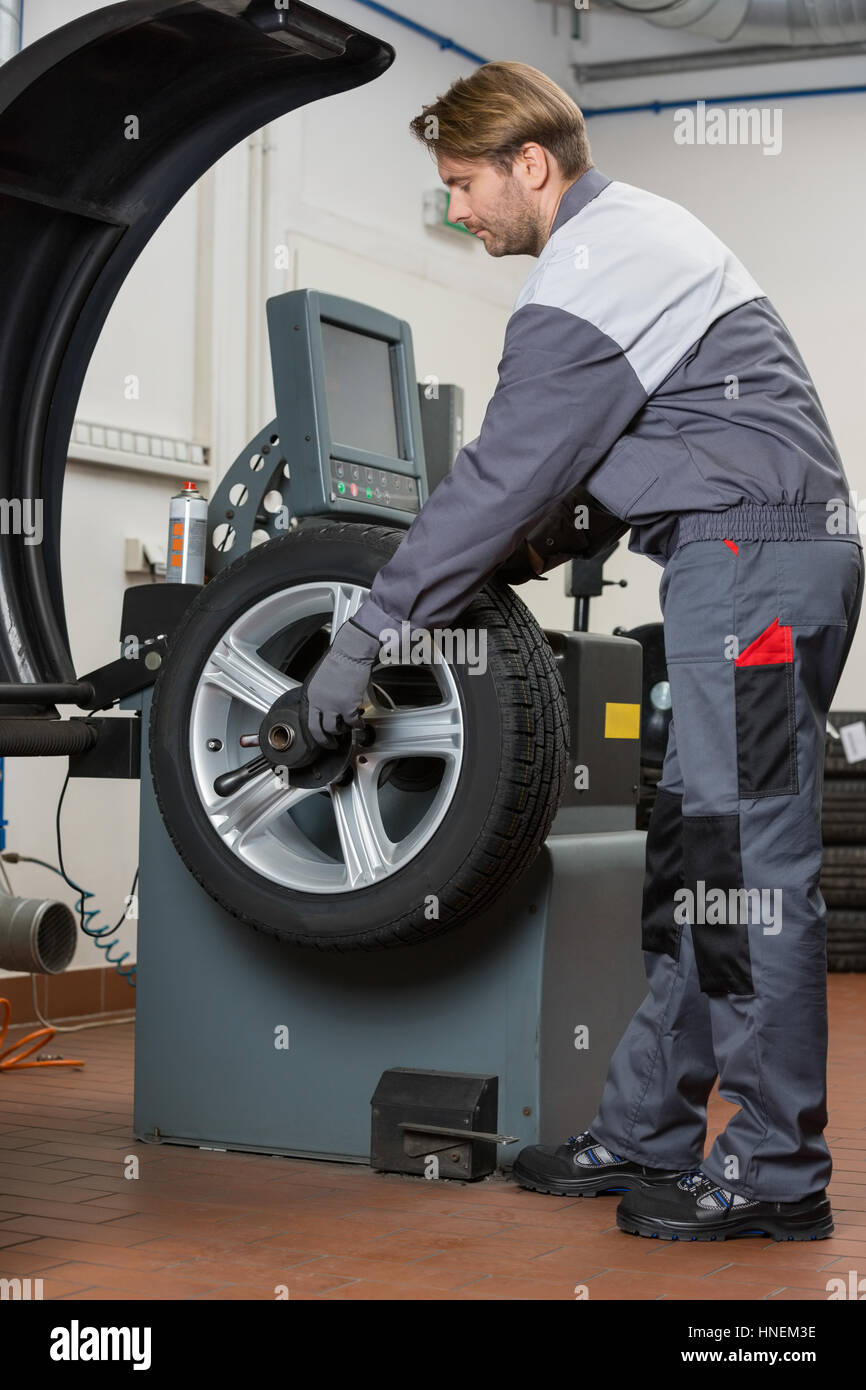 Side view of male mechanic repairing car's wheel in workshop Stock ...