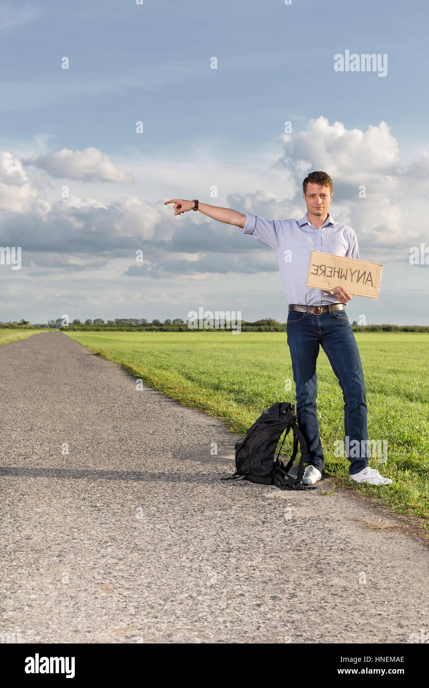 Full length portrait of young man with anywhere sign gesturing on ...