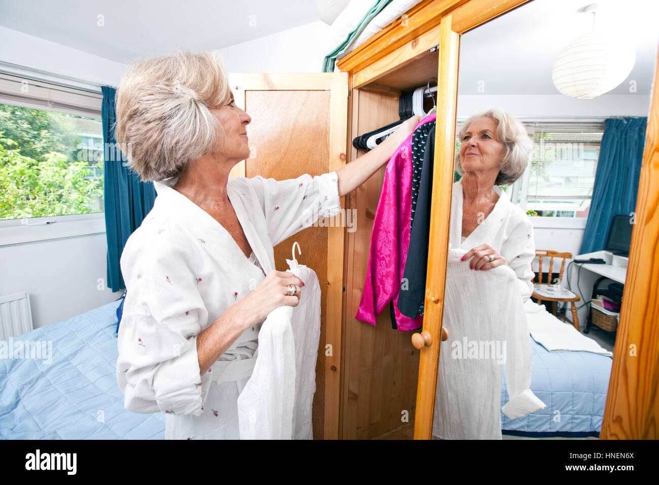 Senior woman selecting dress from closet at home Stock Photo - Alamy
