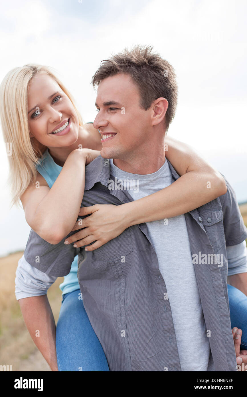 Happy young man giving piggyback ride to woman on field Stock Photo - Alamy