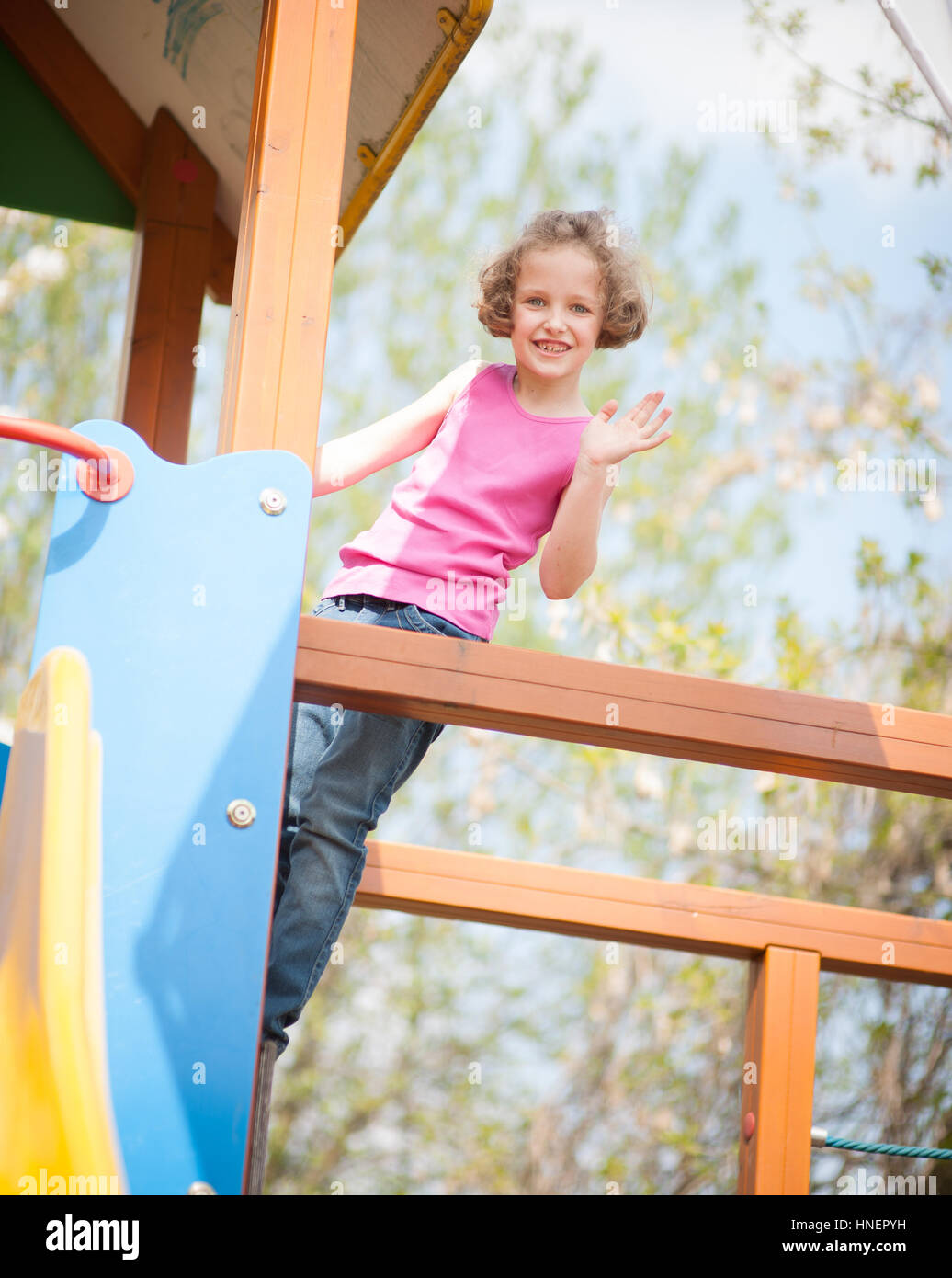 Young girl climbing on childrens playground and waving at camera Stock ...