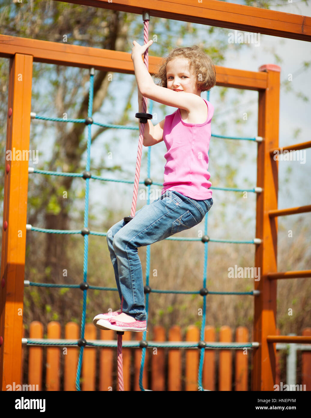 Young girl climbing rope in playground Stock Photo - Alamy