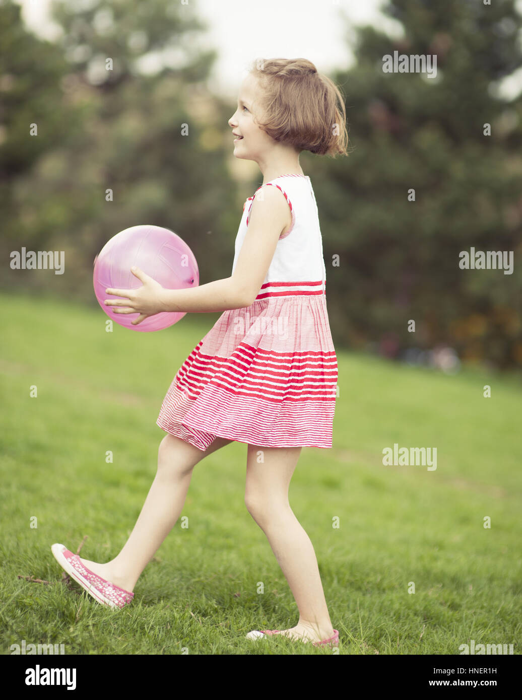 Young girl playing with purple ball in the park Stock Photo - Alamy