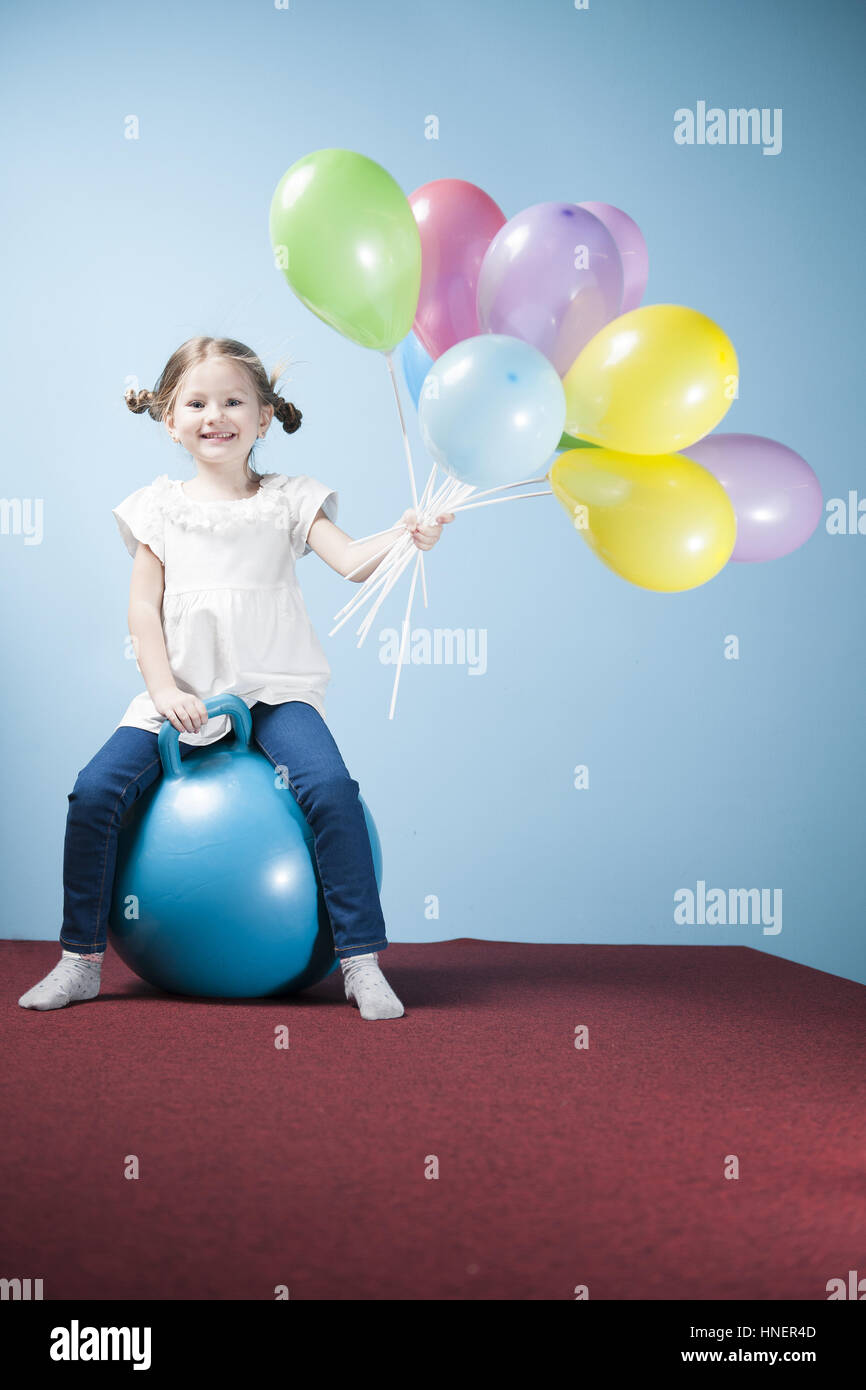 Young girl holding balloons on a hoppity horse Stock Photo - Alamy