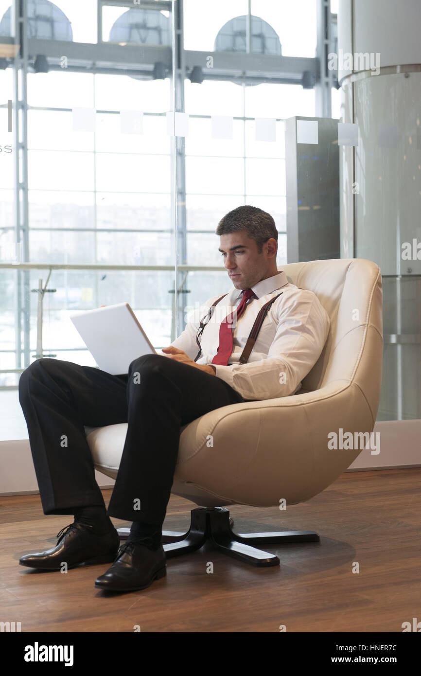 Businessman in arm chair working on laptop Stock Photo - Alamy