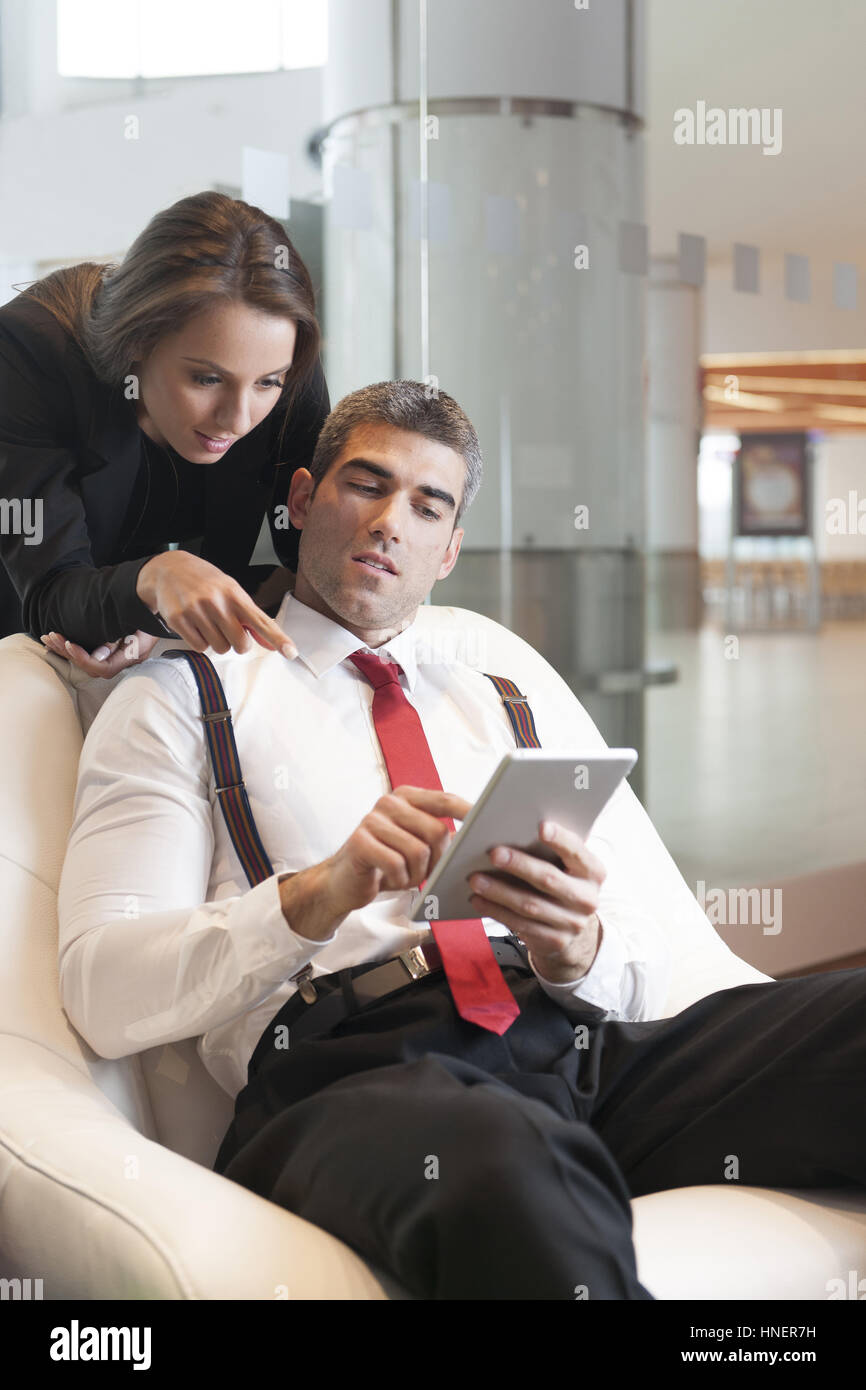 Businesswoman looking over male colleagues shoulder pointing at digital ...